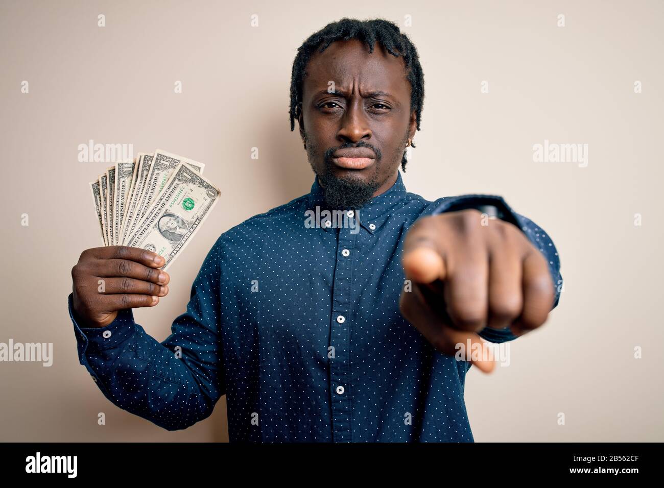 Young african american man holding bunch of dollars banknotes over ...