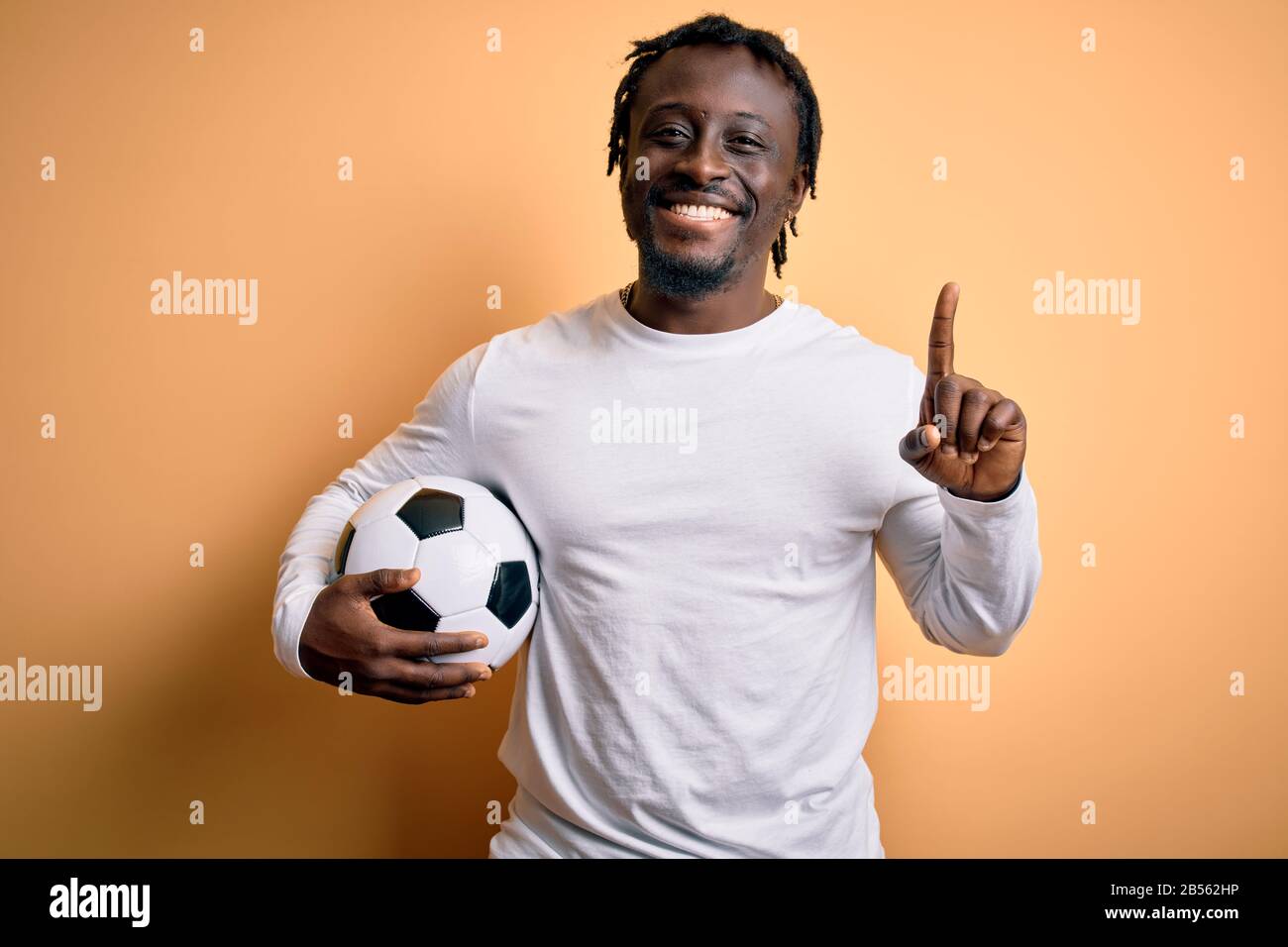 Young african american player man playing soccer holding football ball ...