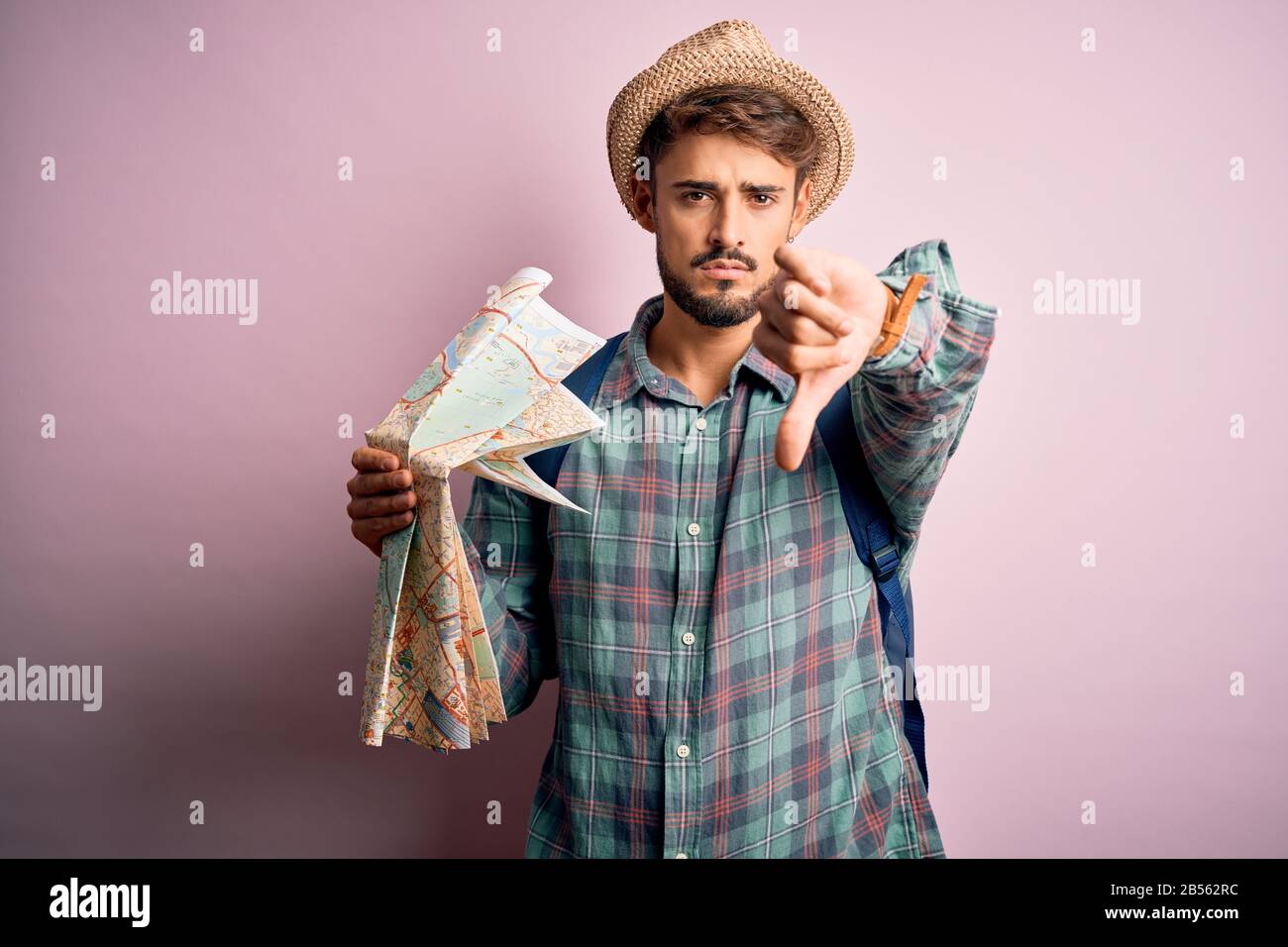 Young tourist man on vacation wearing hat holding city map standing ...