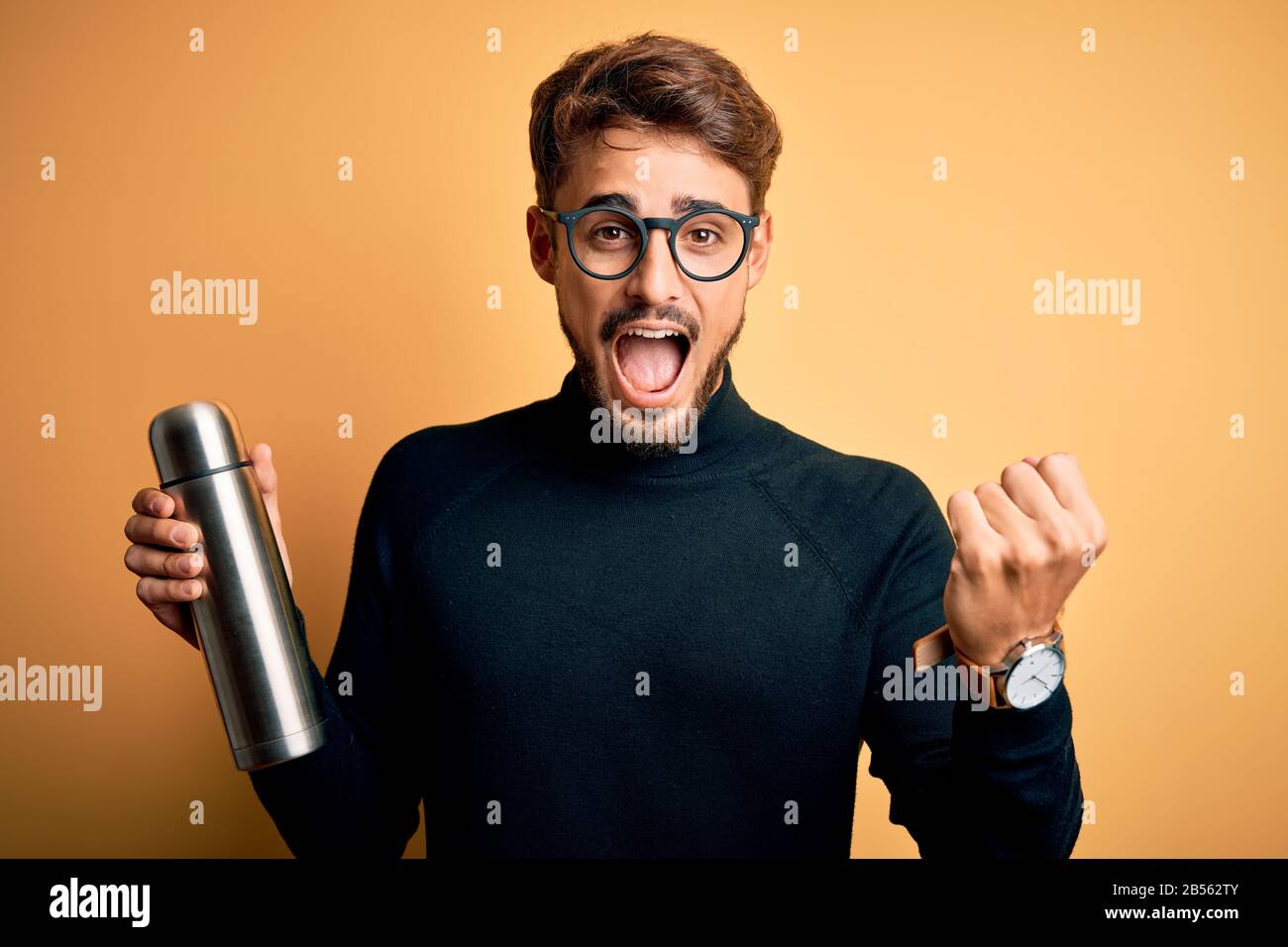 Young man on vacation wearing glasses holding metallic thermo wih water ...