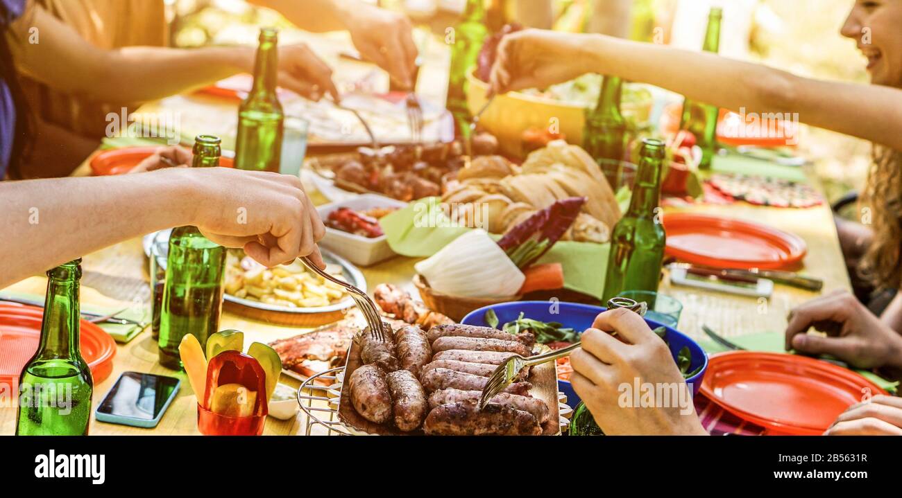 Happy friends eating barbecue meat outdoor in city park on summer time ...