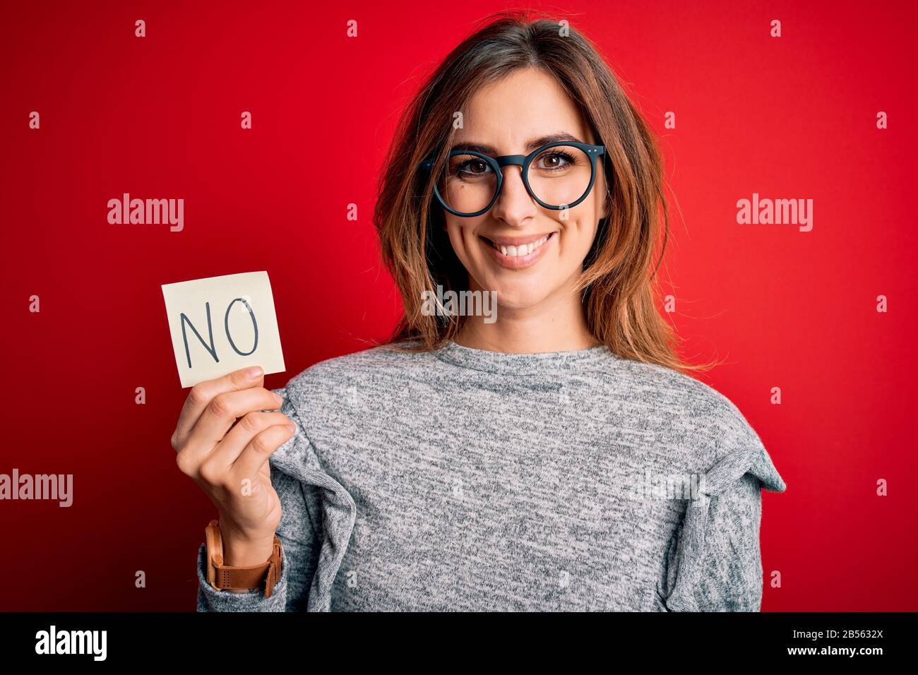 Young beautiful brunette woman holding reminder paper with no message ...