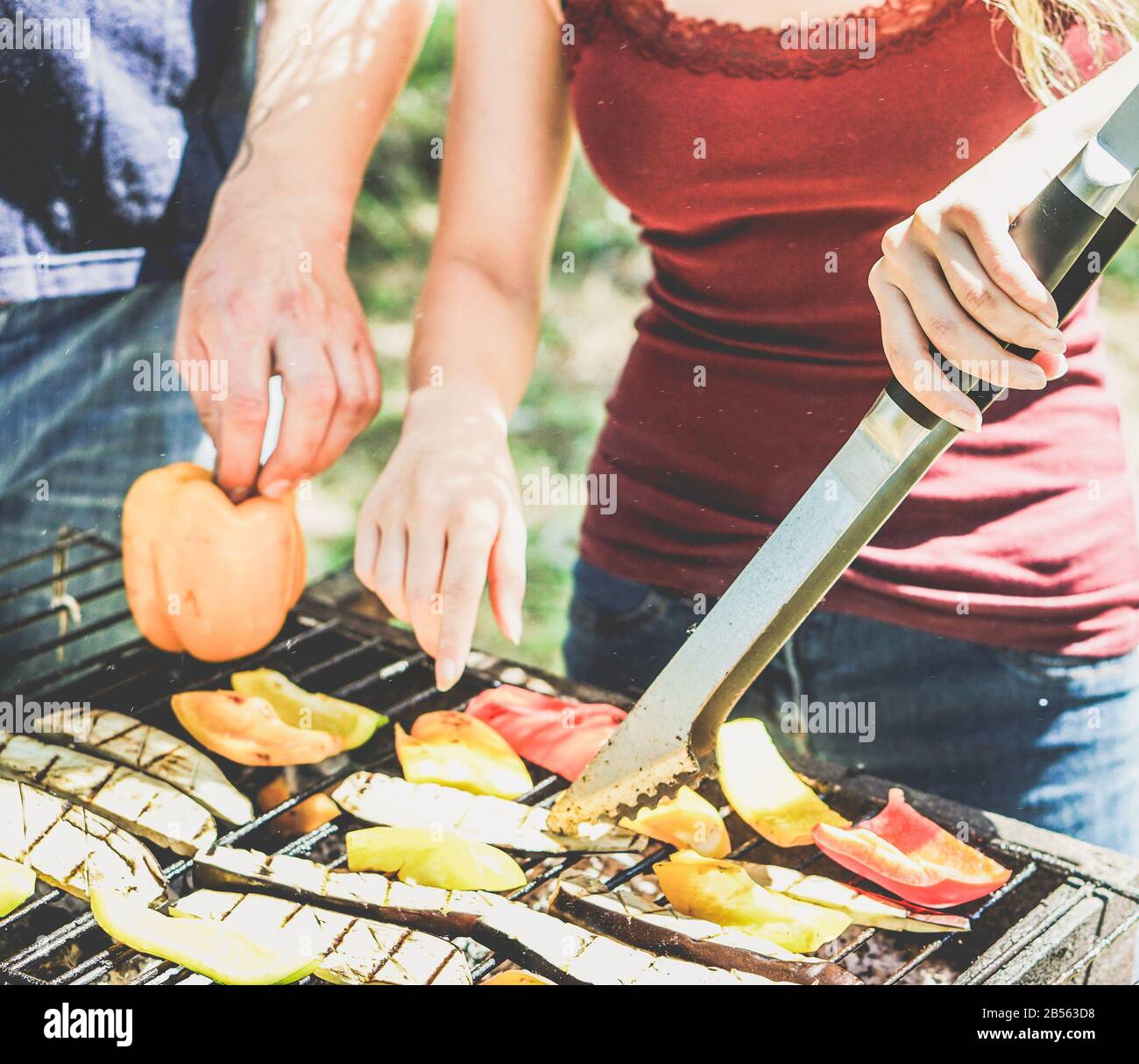 Young woman cooking vegetables at barbecue dinner outdoor - Couple ...