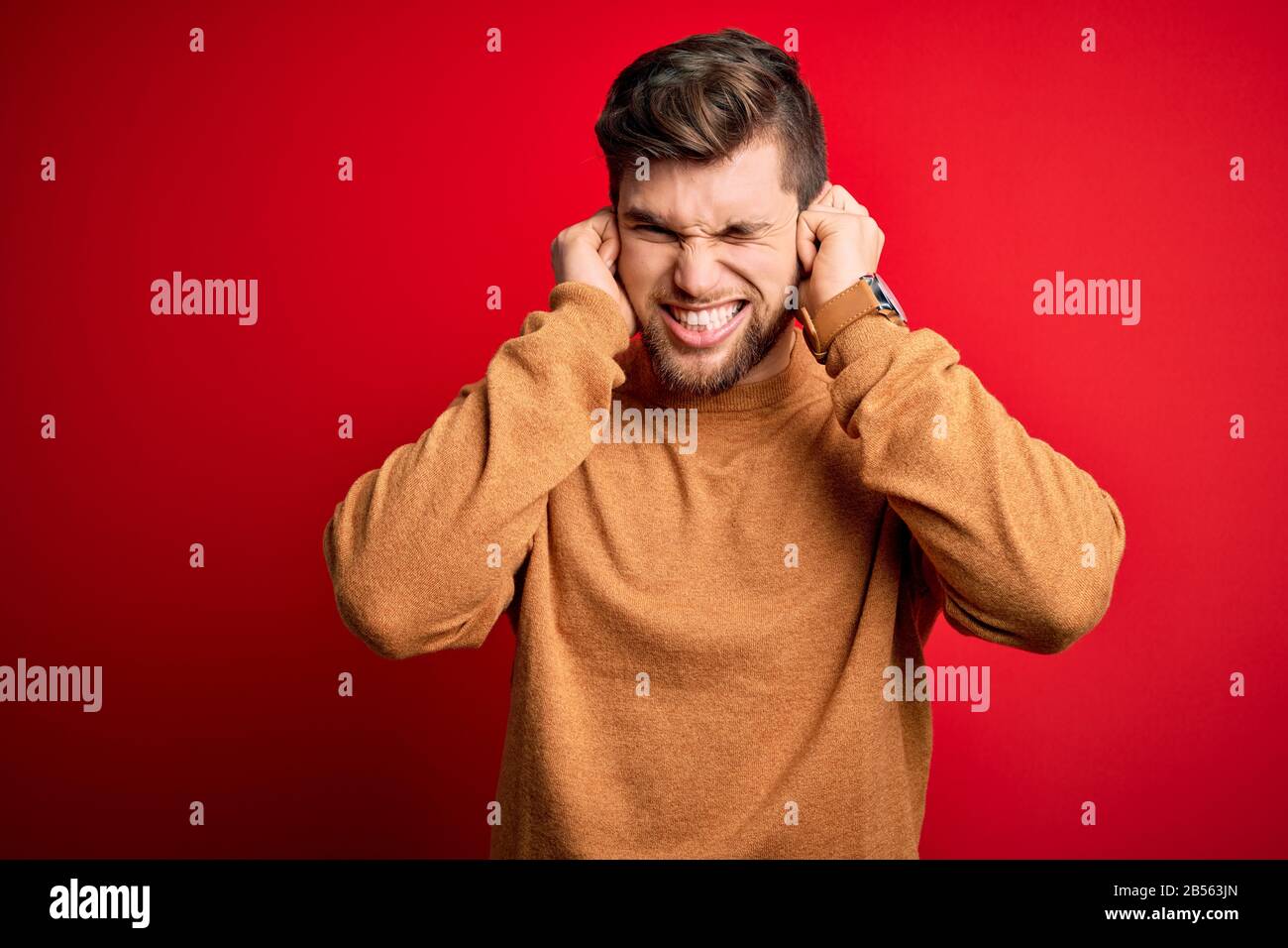 Young blond man with beard and blue eyes wearing casual sweater over ...