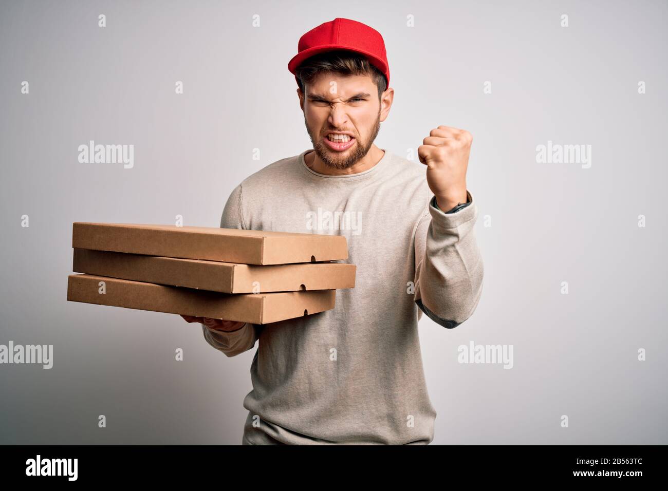 Young blond delivery man with beard and blue eyes holding cardboards of ...