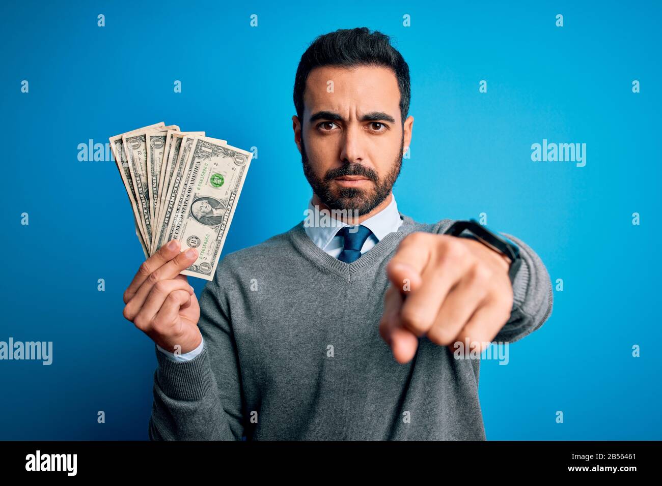 Young handsome man with beard holding bunch of dollars banknotes over ...