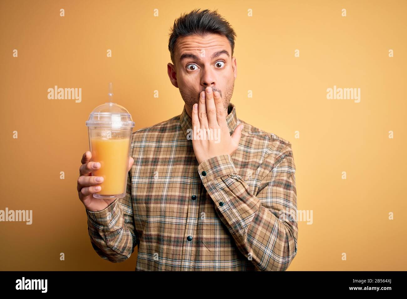 Young handsome man drinking healthy orange juice using straw over ...