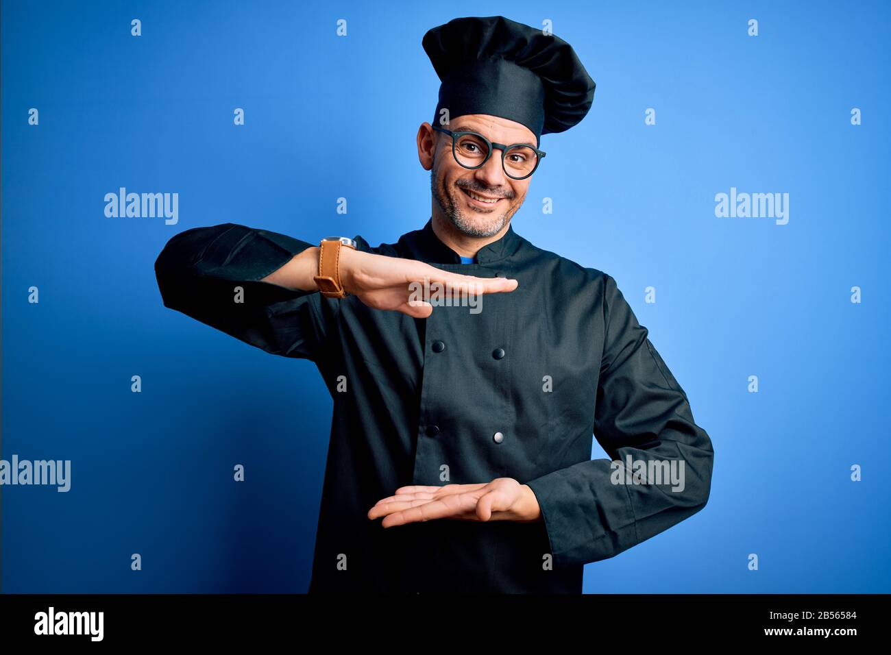 Young handsome chef man wearing cooker uniform and hat over isolated ...
