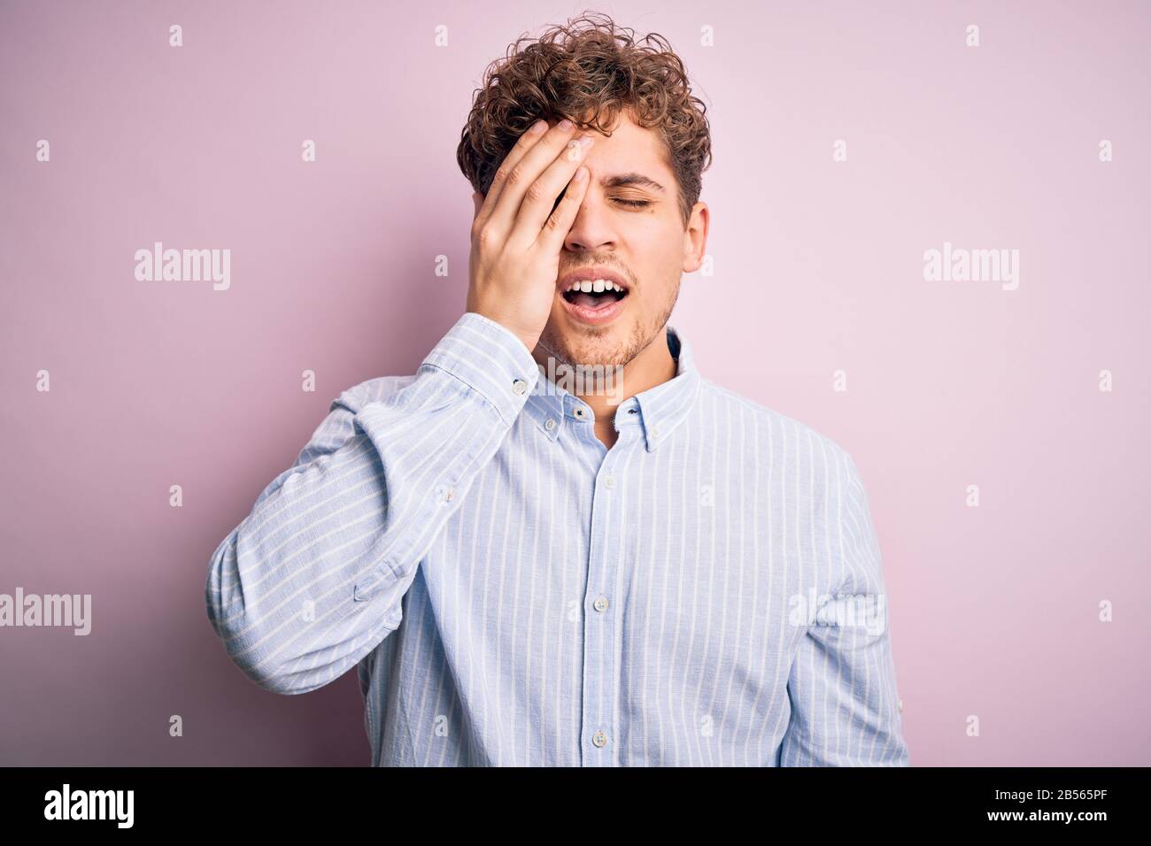 Young blond handsome man with curly hair wearing striped shirt over ...