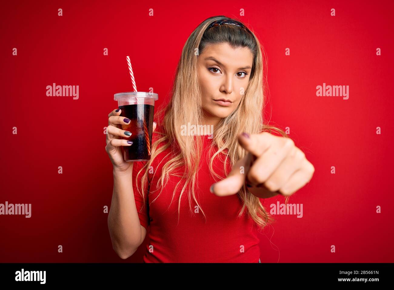 Young beautiful blonde woman drinking cola fizzy beverage using straw ...