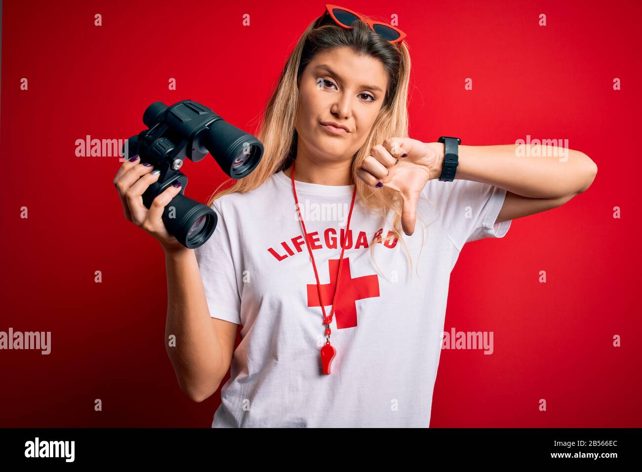 Young beautiful blonde lifeguard woman using binoculars and whistle ...