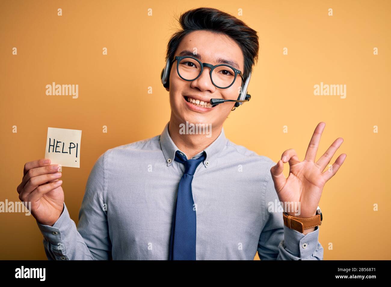 Young handsome chinese call center agent man overworked using headset ...