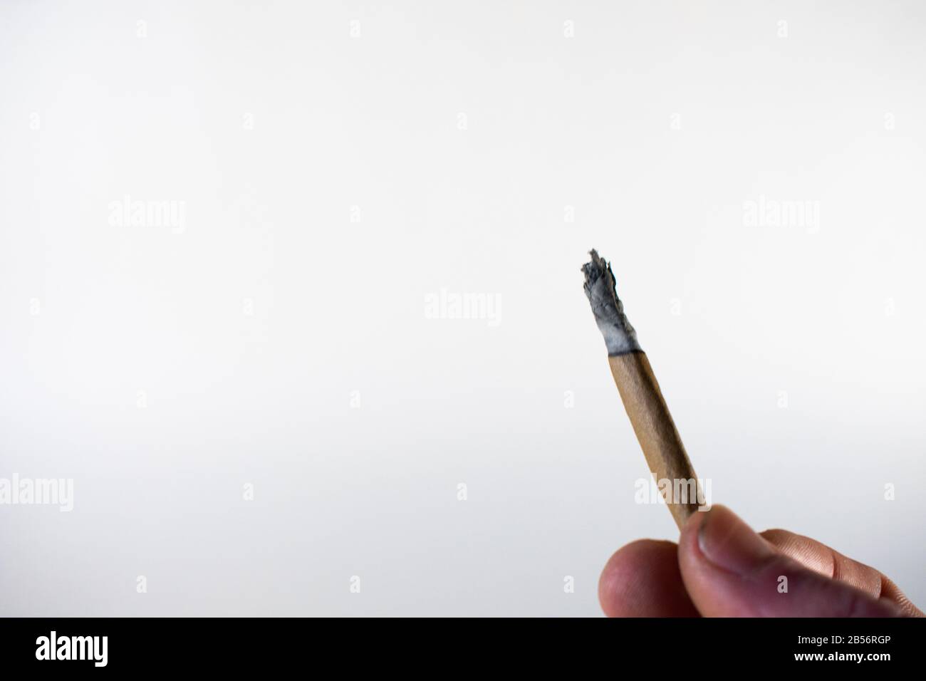 A Hand Holding a Lit Brown Cannabis Cigar With Grey Ash on Top on a ...