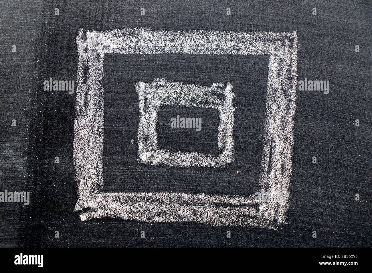 White color chalk hand drawing in square shape on black board ...