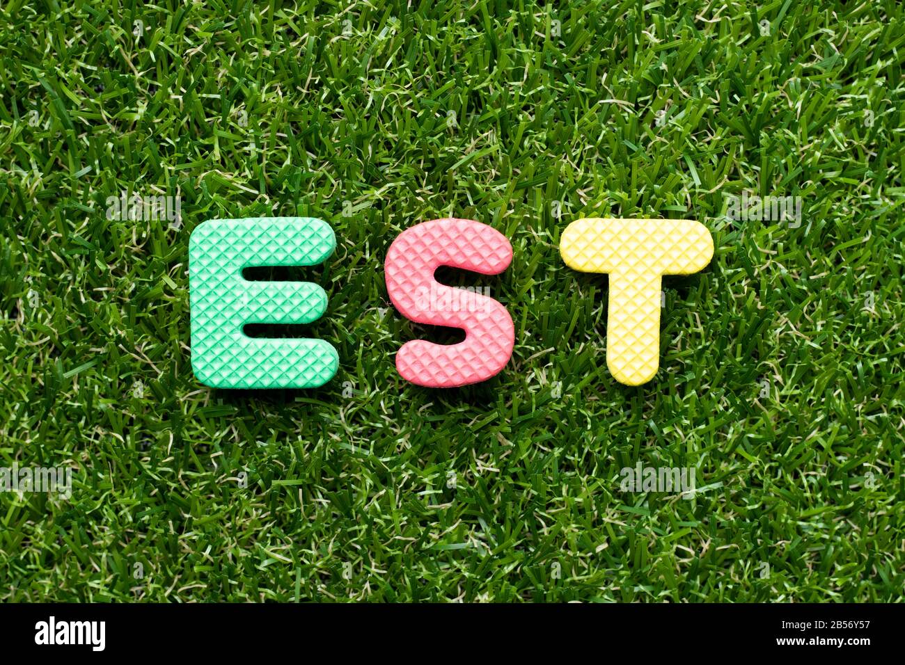 Toy foam letter in word est on green grass background Stock Photo - Alamy