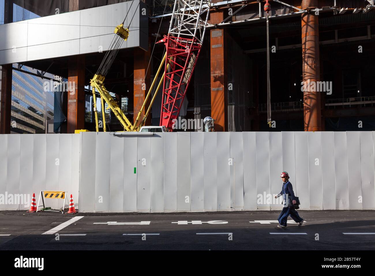 A construction worker walks past the wall of a construction site early ...