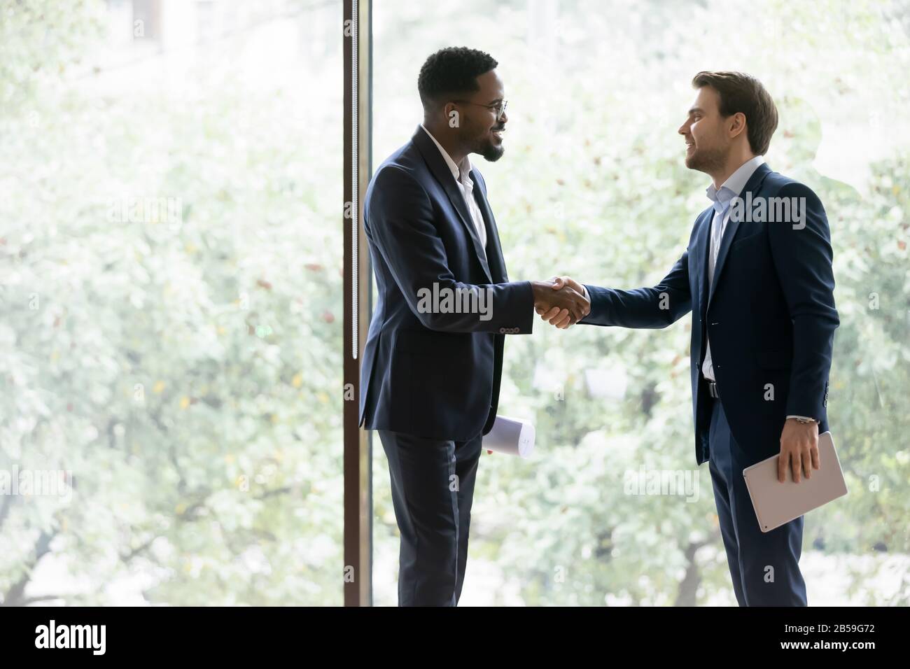 Happy diverse businessmen handshake closing deal after negotiations ...