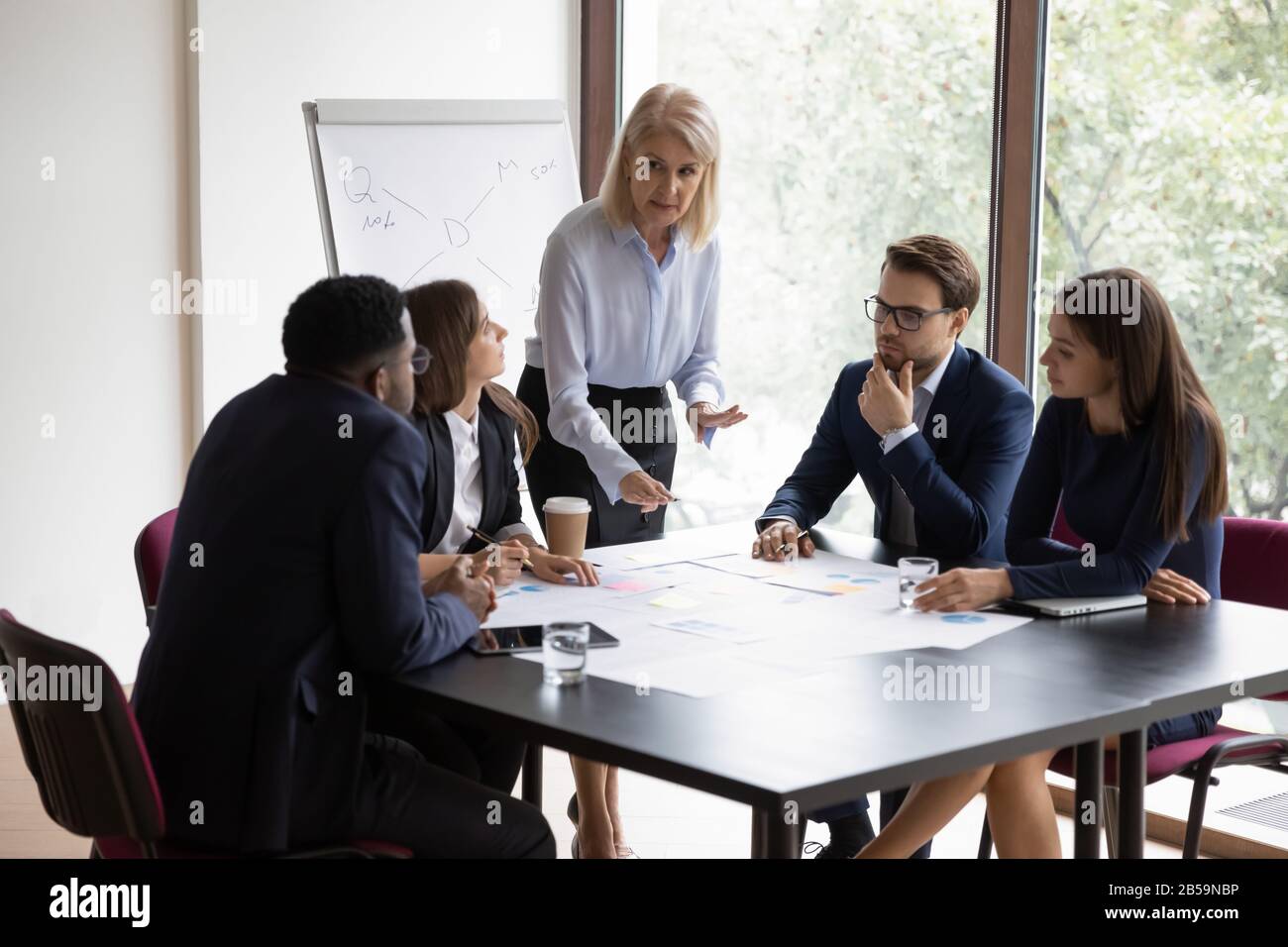 Focused female boss brainstorm with diverse colleagues at briefing ...
