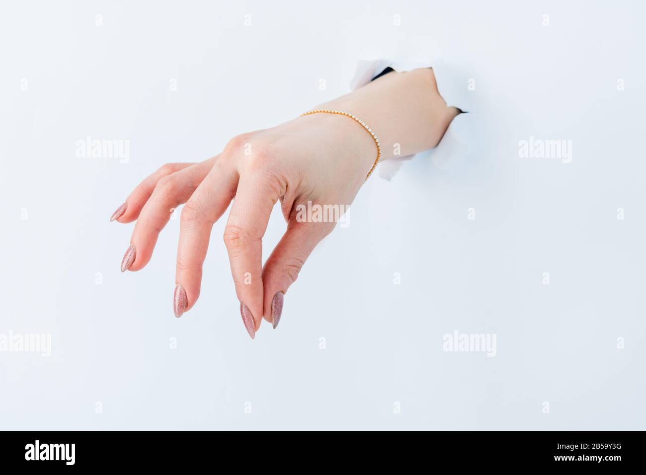women's hand through hole in white paper Stock Photo - Alamy