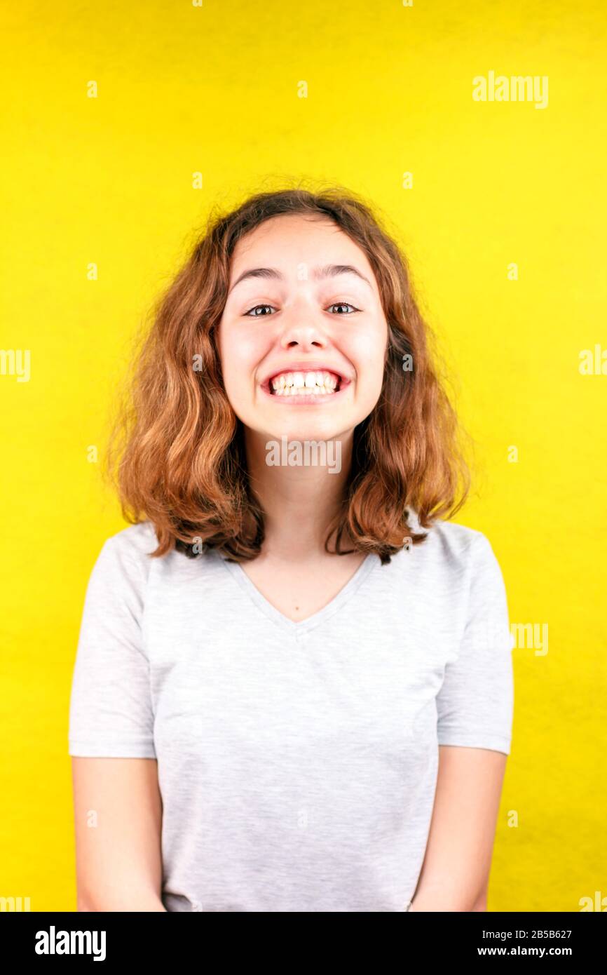 Cute teenager girl with funny face smiling with big eyes to the camera ...