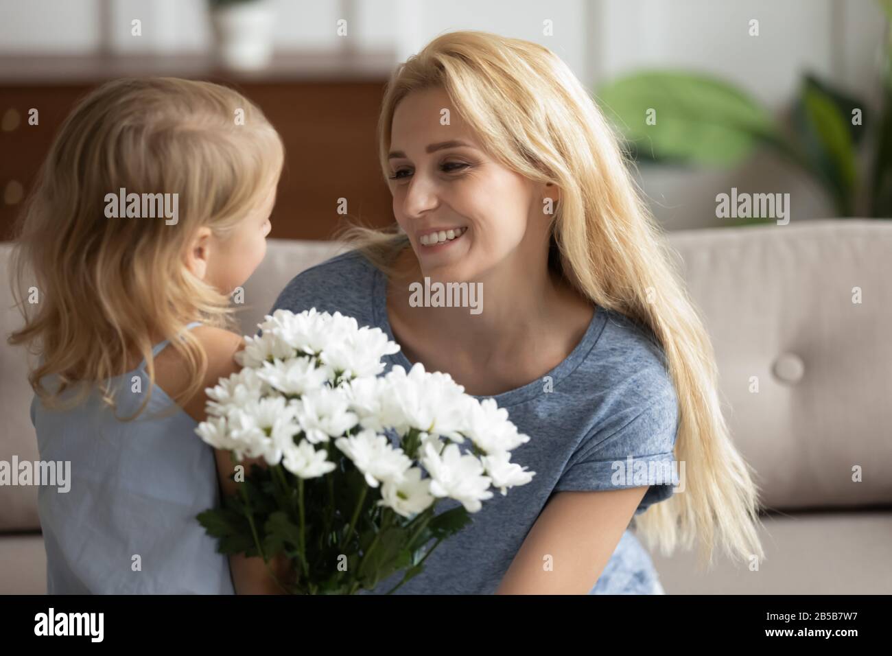 Cute little girl congratulating young mom presenting flowers Stock ...
