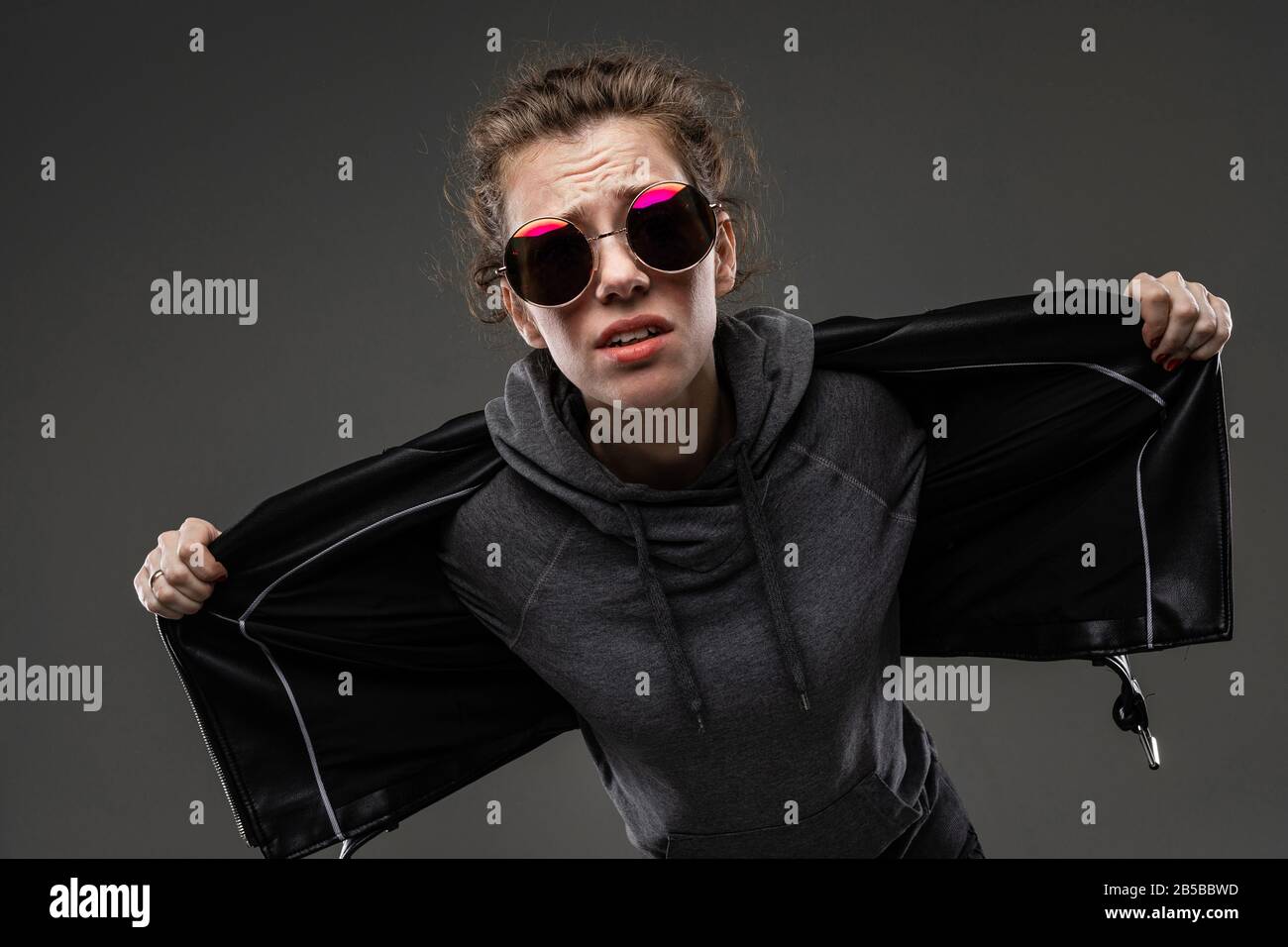 A young girl with rough facial features in a black jacket isolated on ...