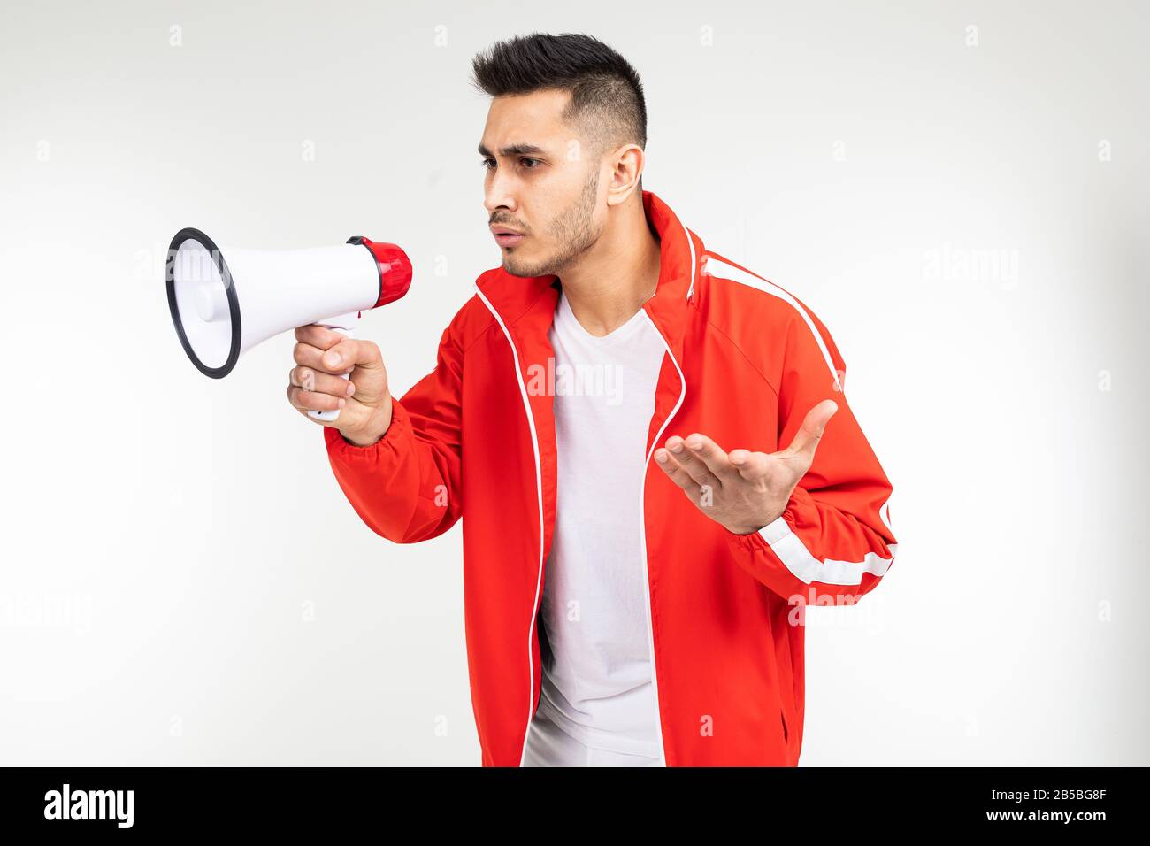 portrait of a young man with a loudspeaker in his hands on a white ...