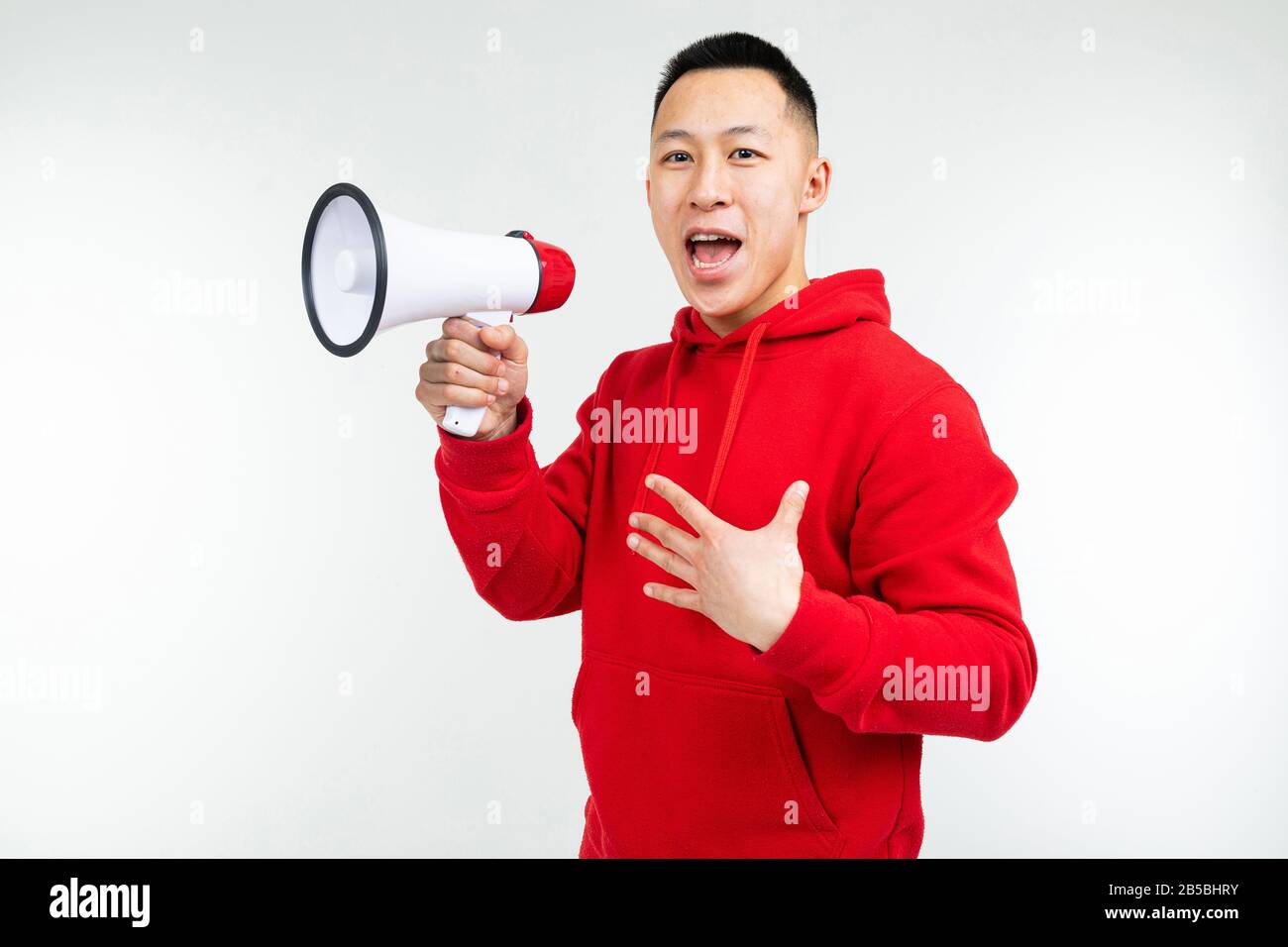 portrait of a young man with a loudspeaker in his hands on a white ...