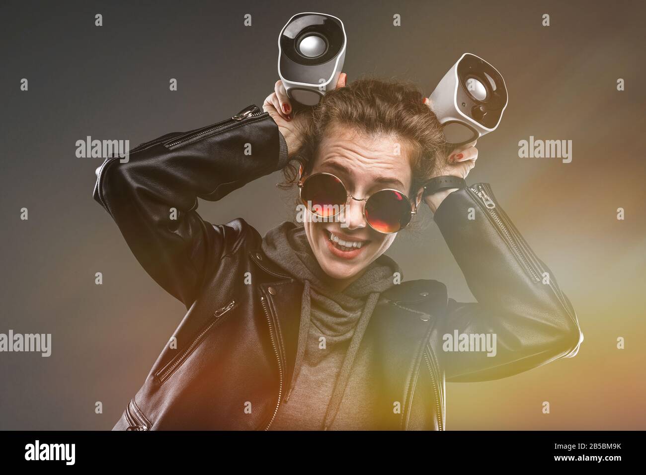 A young girl with rough facial features in a black jacket listens to ...