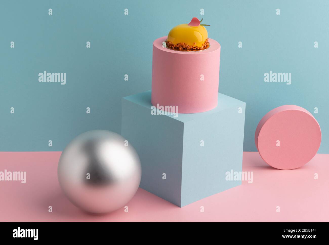Ball, cube, cylinder and yellow mousse cake on blue background Stock ...
