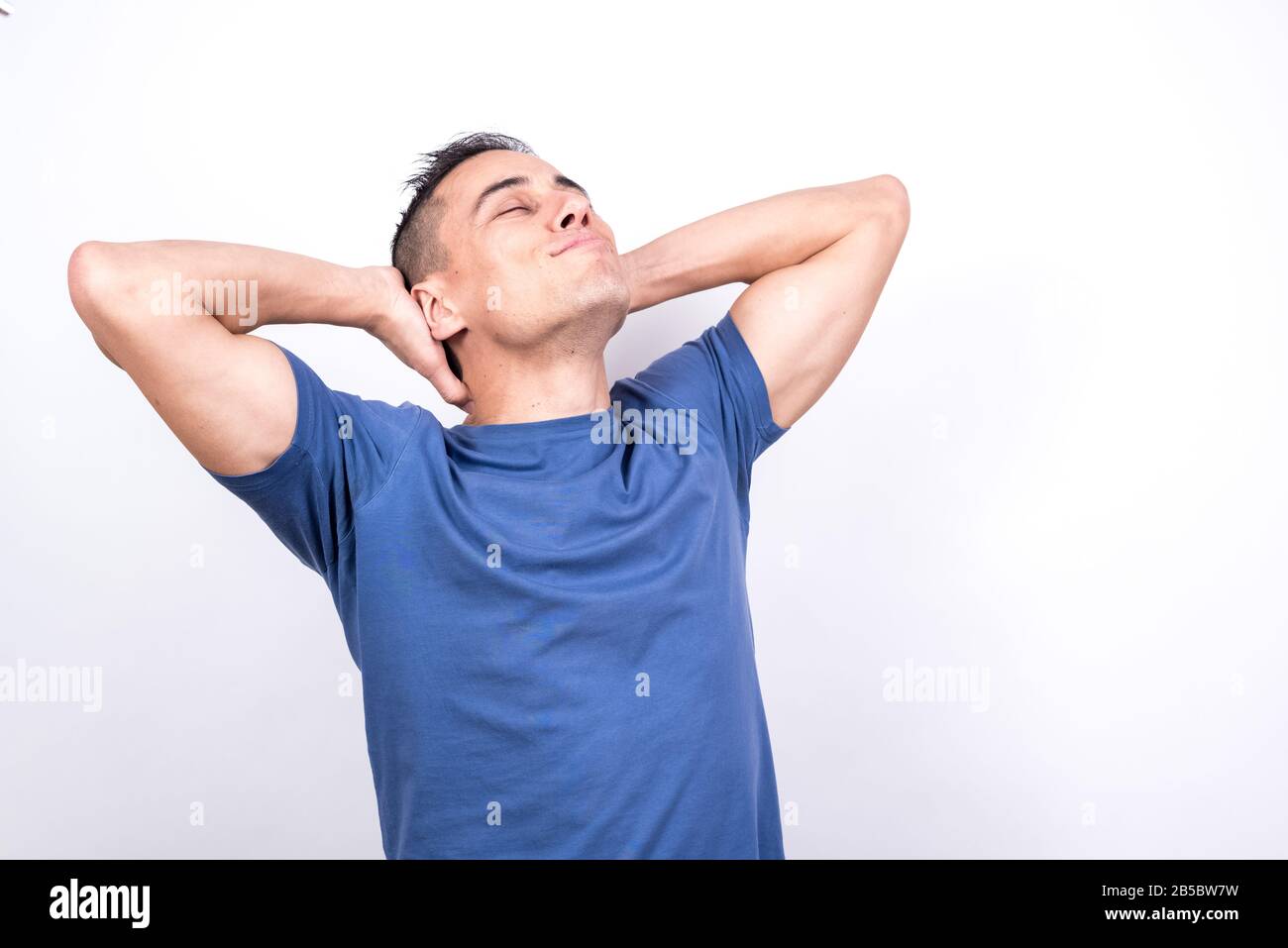 Relaxed man leaning back with his hands on the back of his neck.. White ...