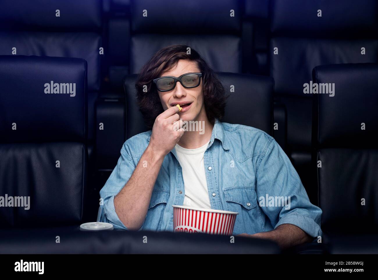 Enjoying alone time in movies. Cheerful young man with 3D glasses and ...
