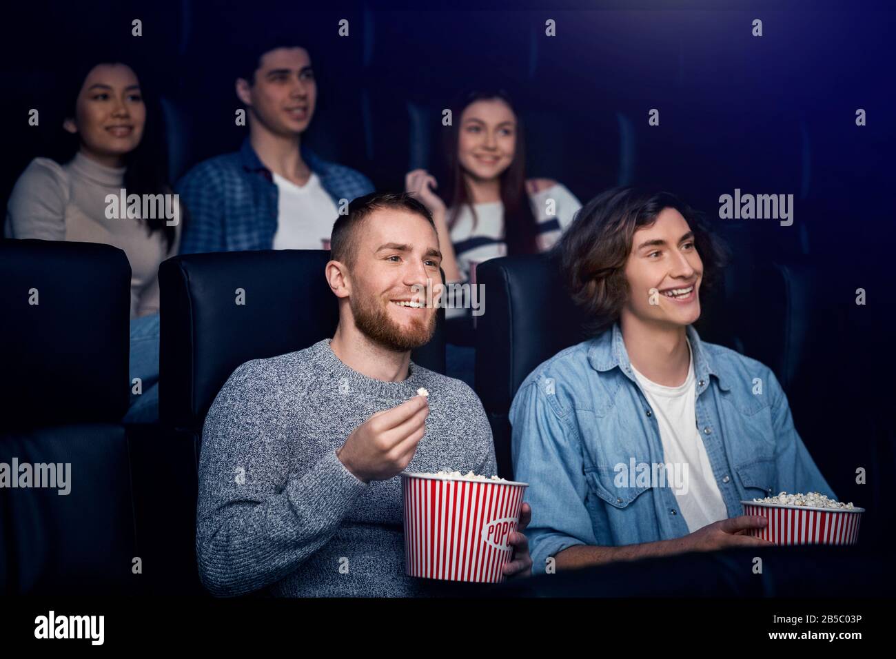 Entertainment concept. Cheerful young people with popcorn enjoying ...