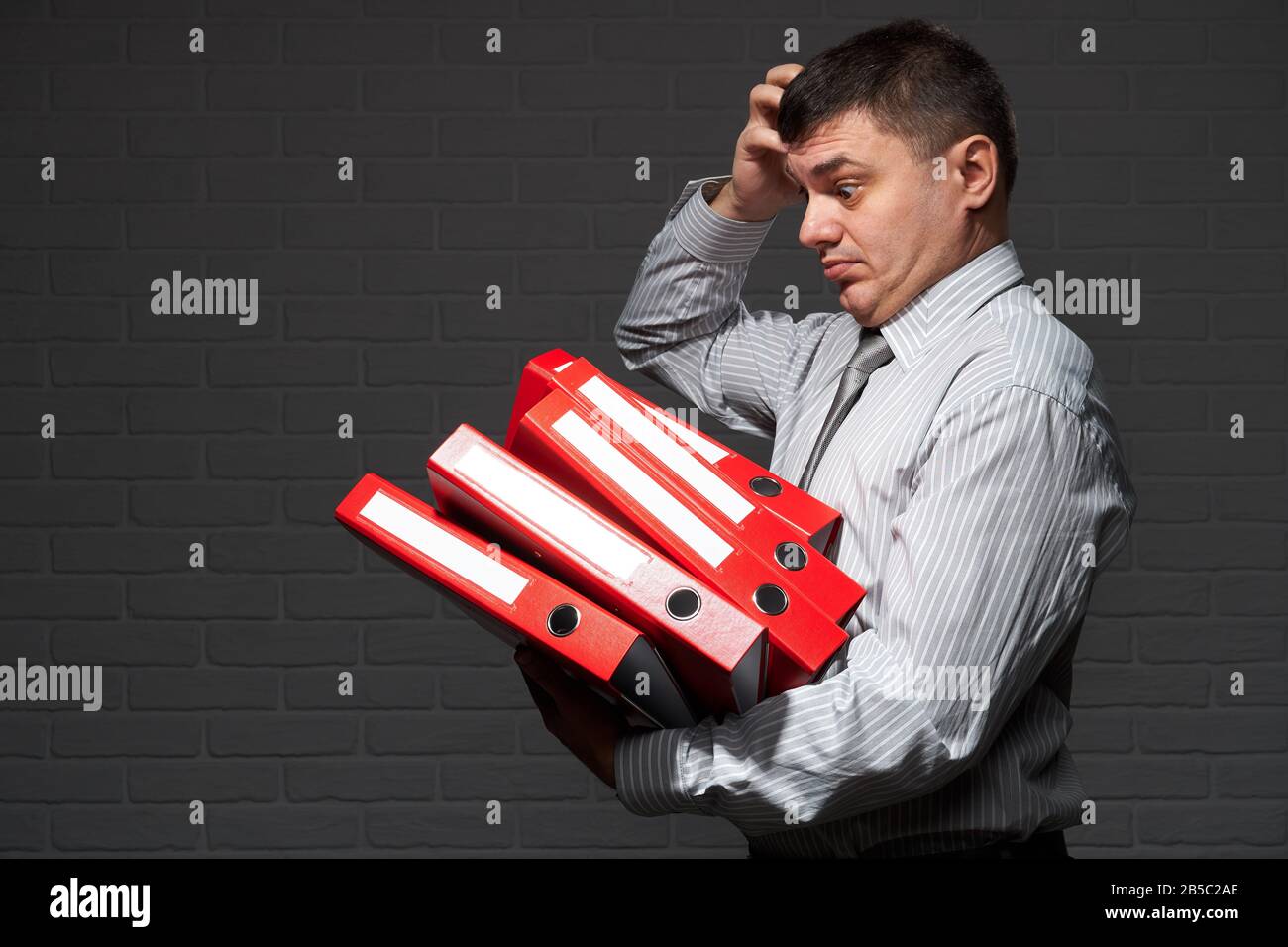 Very busy businessman closeup portrait, posing with red folders ...