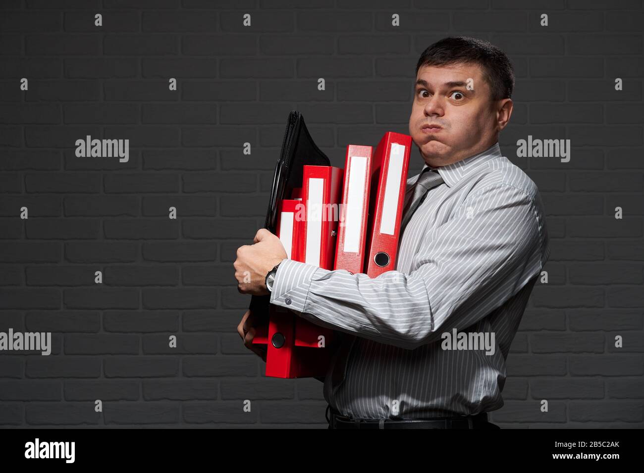 Very busy businessman closeup portrait, posing with red folders ...