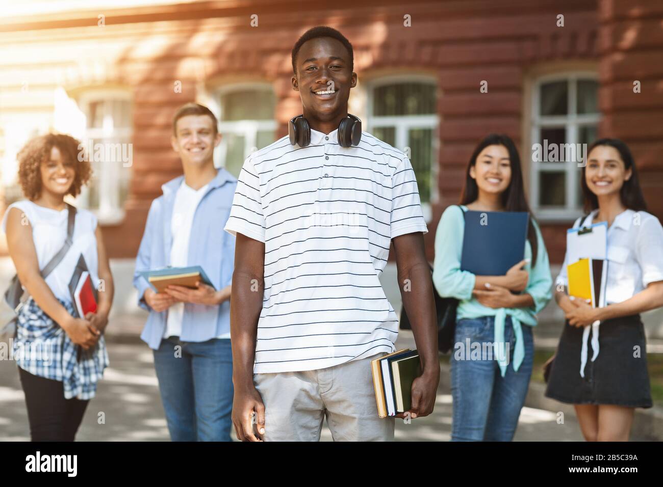 Happy African Student Guy Posing With His University Friends Outdoors ...