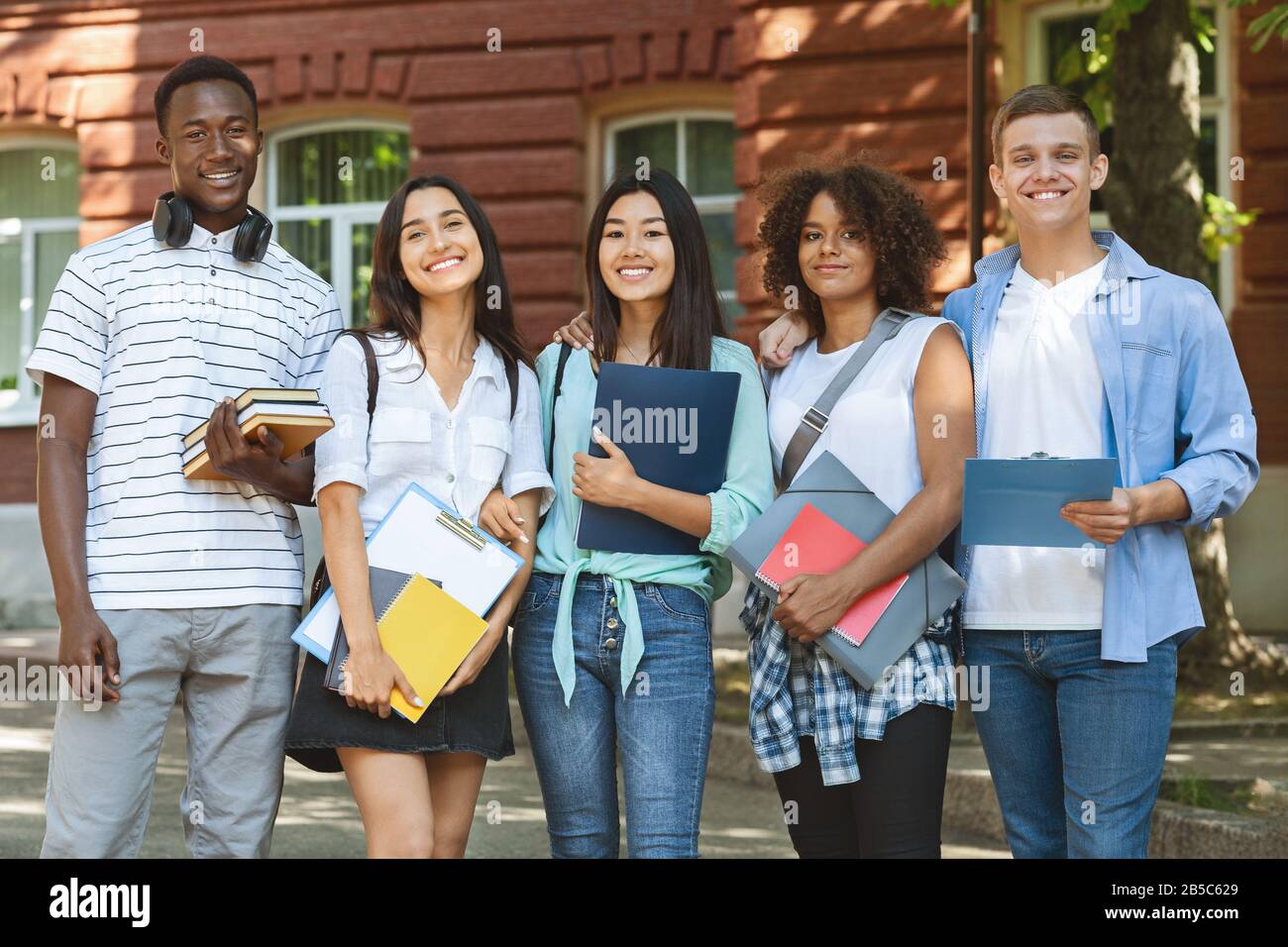 Group of happy international students posing over university background ...
