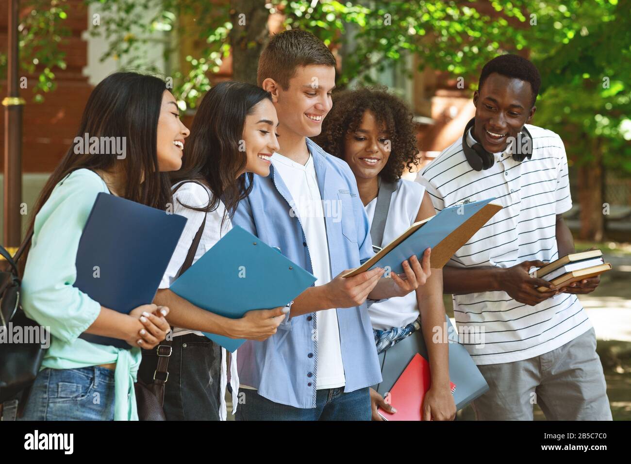 Group Of Cheerful International Students Standing Outdoors, Checking ...