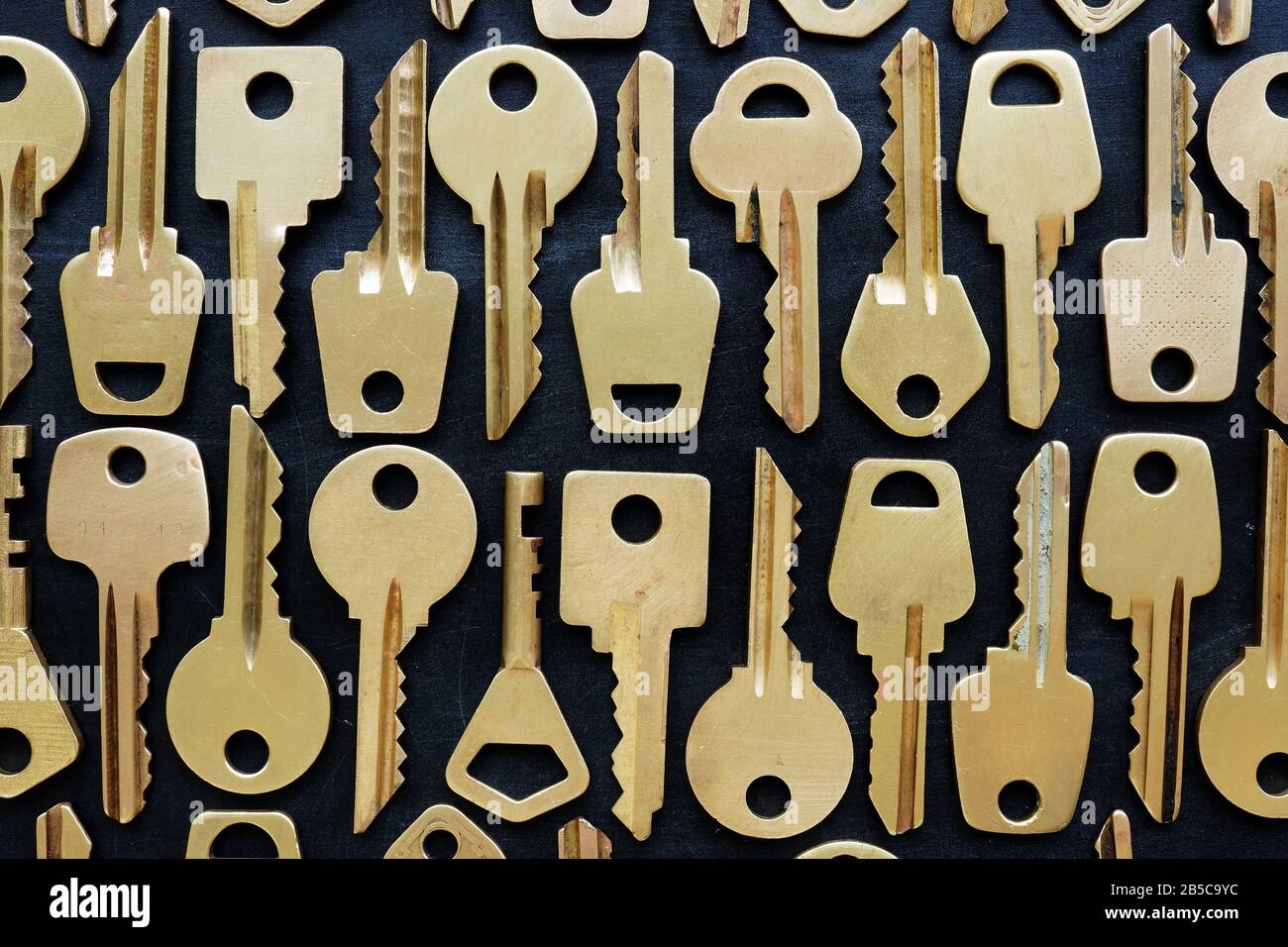 Yellow metal keys on the dark background Stock Photo - Alamy