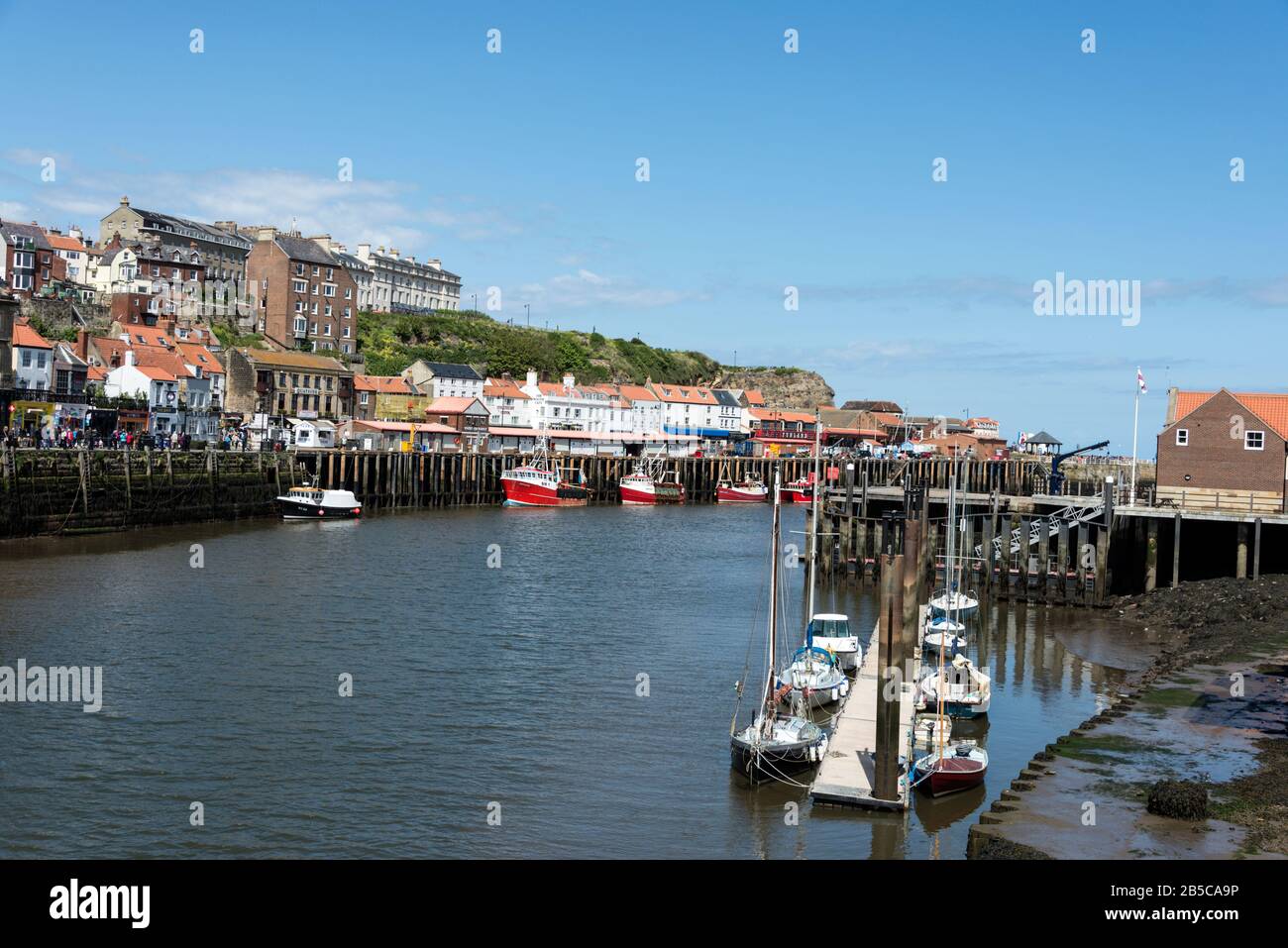 A small fleet of moored red fishing trawlers and other river craft on ...