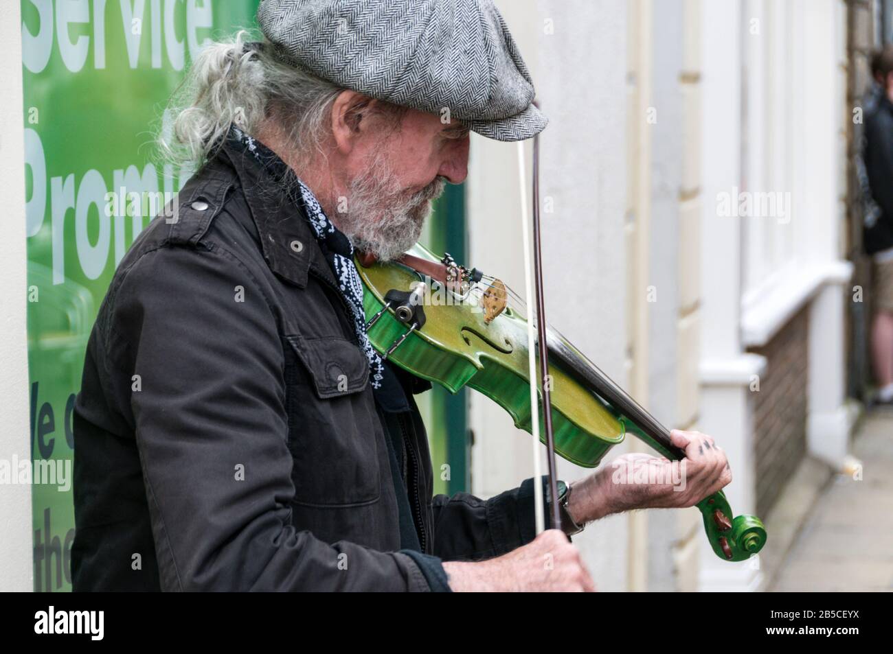 A street busker playing his violin in the streets of Whitby on the east ...