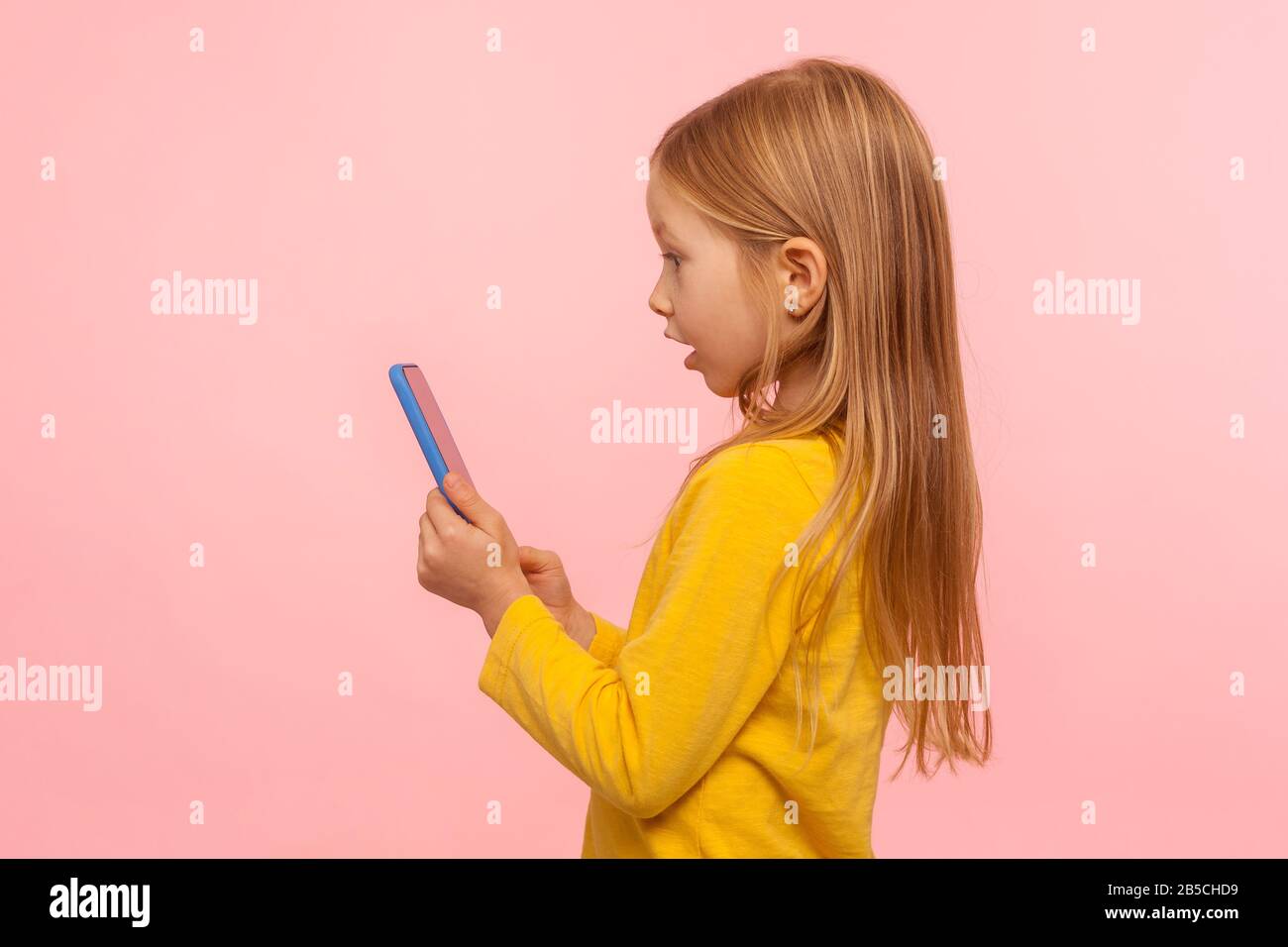 Wow, great app for kids. Side view of astonished little girl using ...