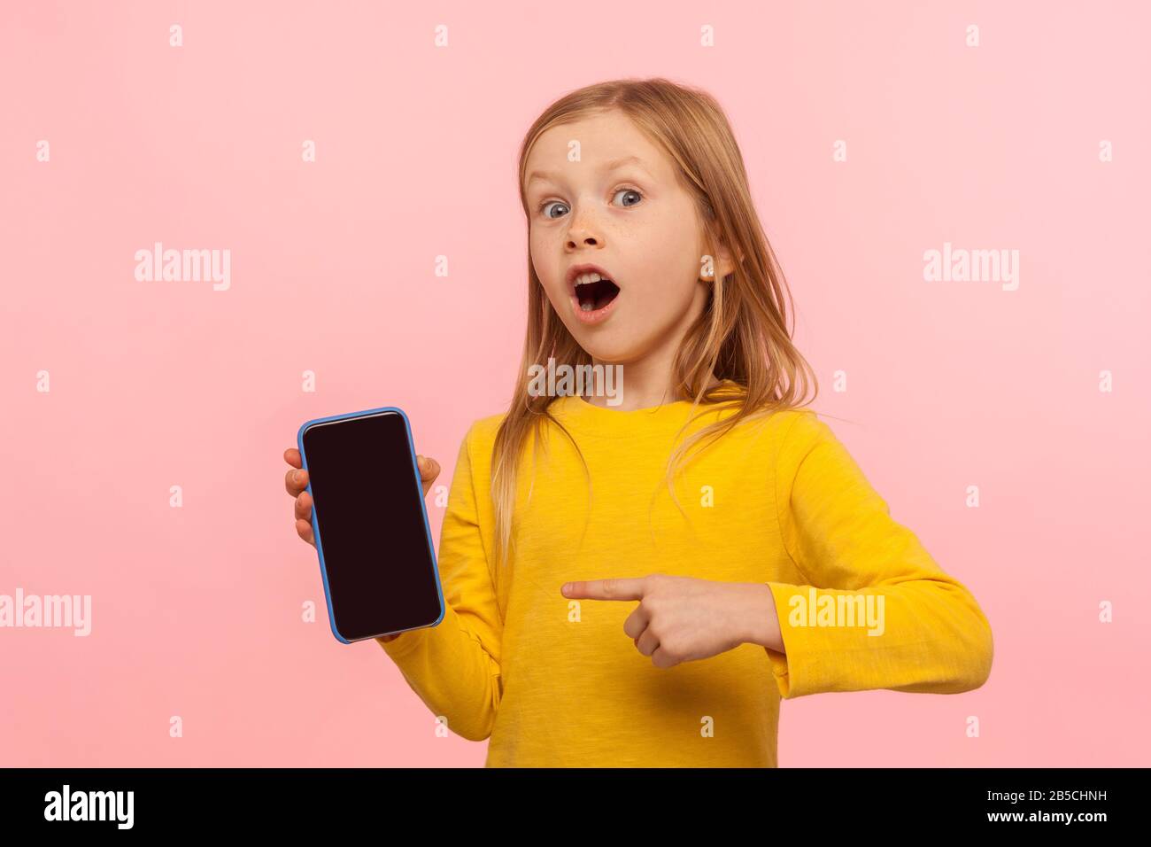 Wow, look at cellphone! Amazed little girl pointing phone and looking ...