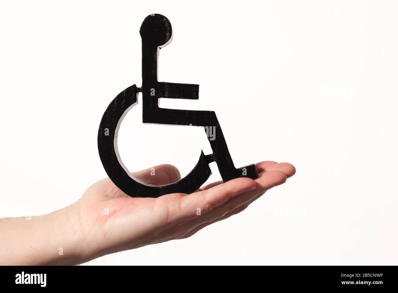 Disabled black shape cutout from wood sat on an open hand. Disability ...