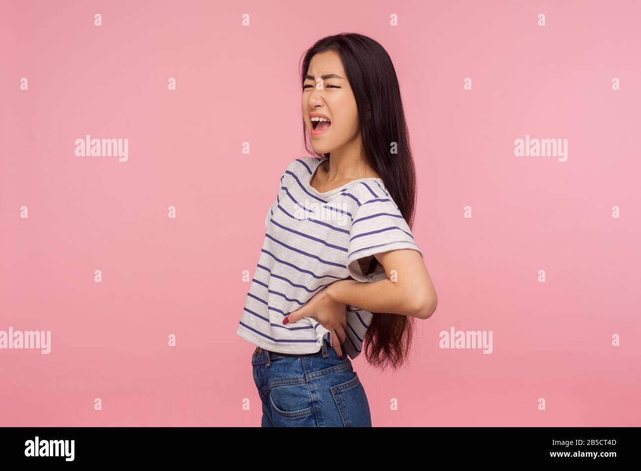 Backache. Unhealthy girl with brunette hair touching back, suffering ...