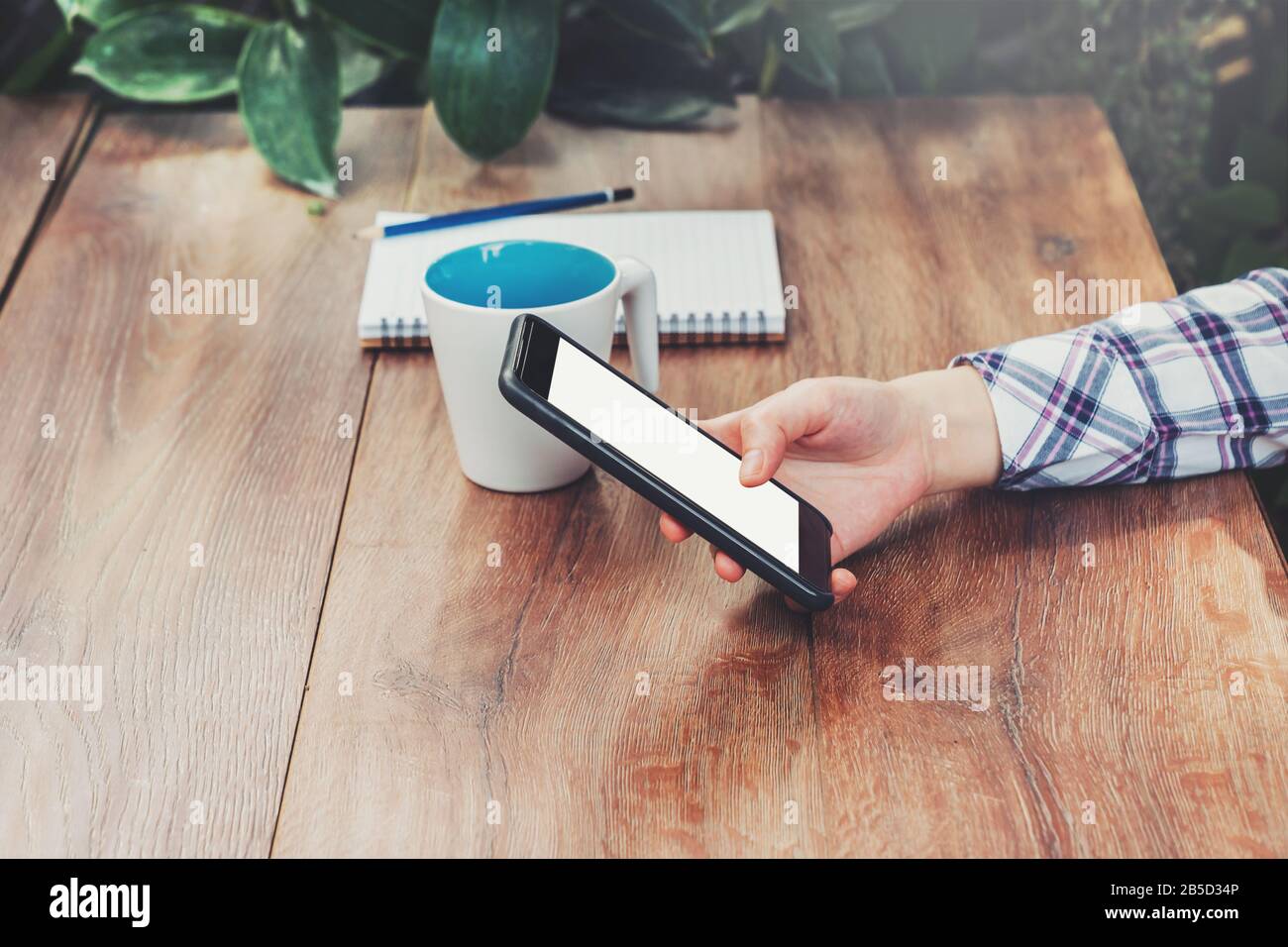 Woman hand using phone on wood table Stock Photo - Alamy