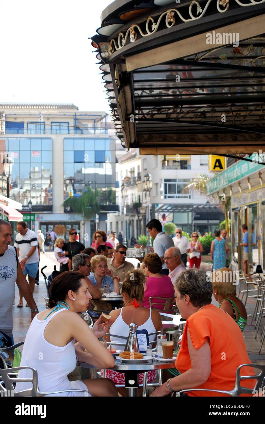 People relaxing at a street cafe serving Churros and chocolate ...