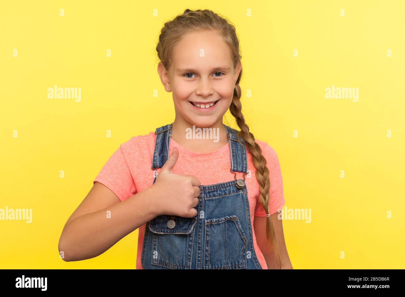I like it! Portrait of charming pleased little girl with braid in denim ...