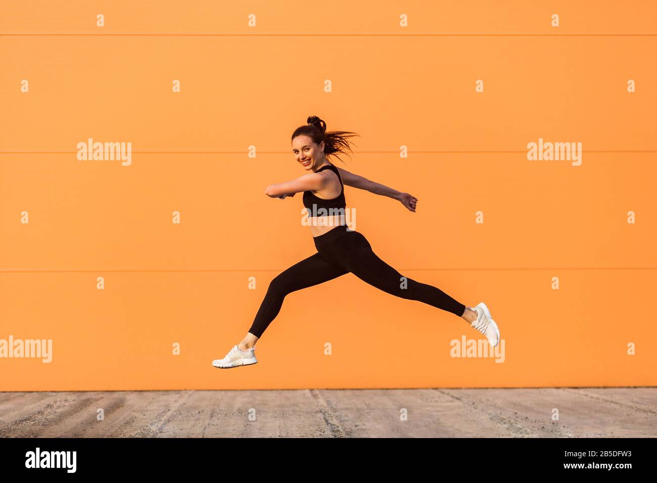 Positive lively vivid girl with fit body in tight sportswear jumping ...