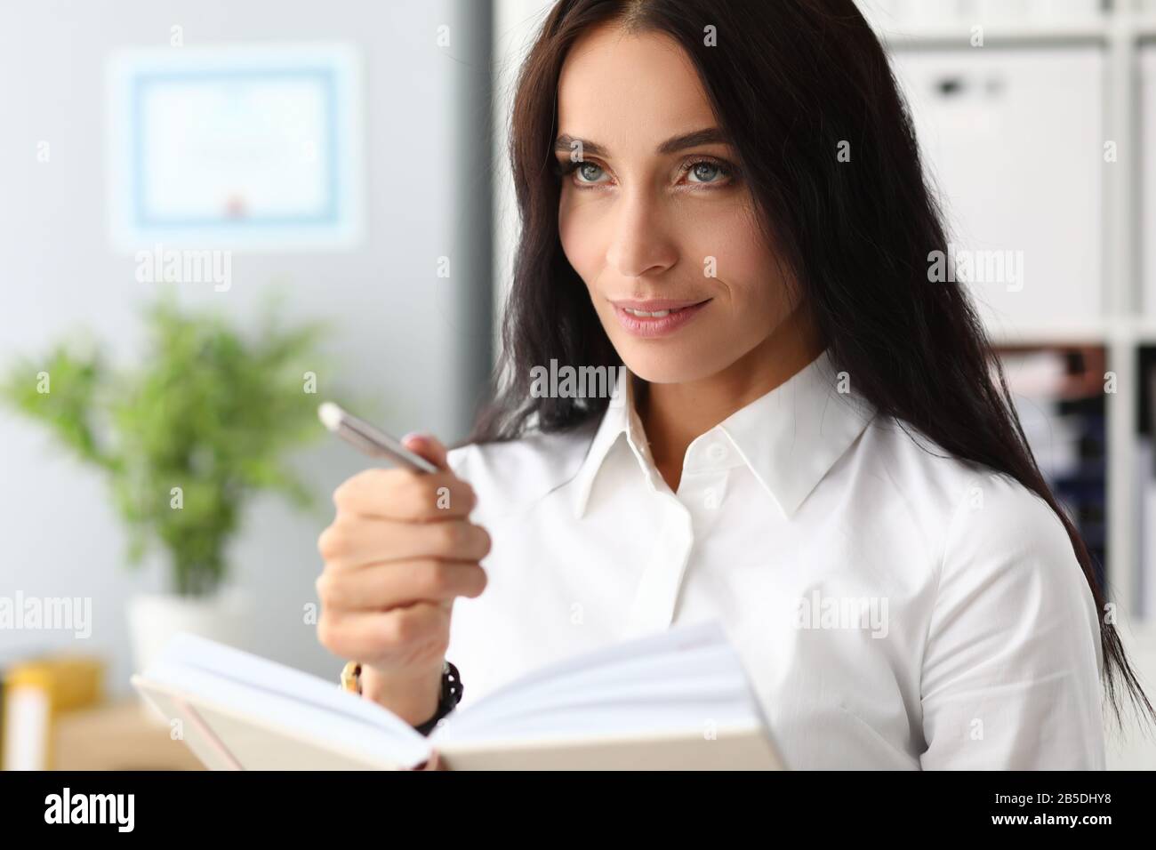 Attractive girl makes diary entries shows with pen Stock Photo - Alamy